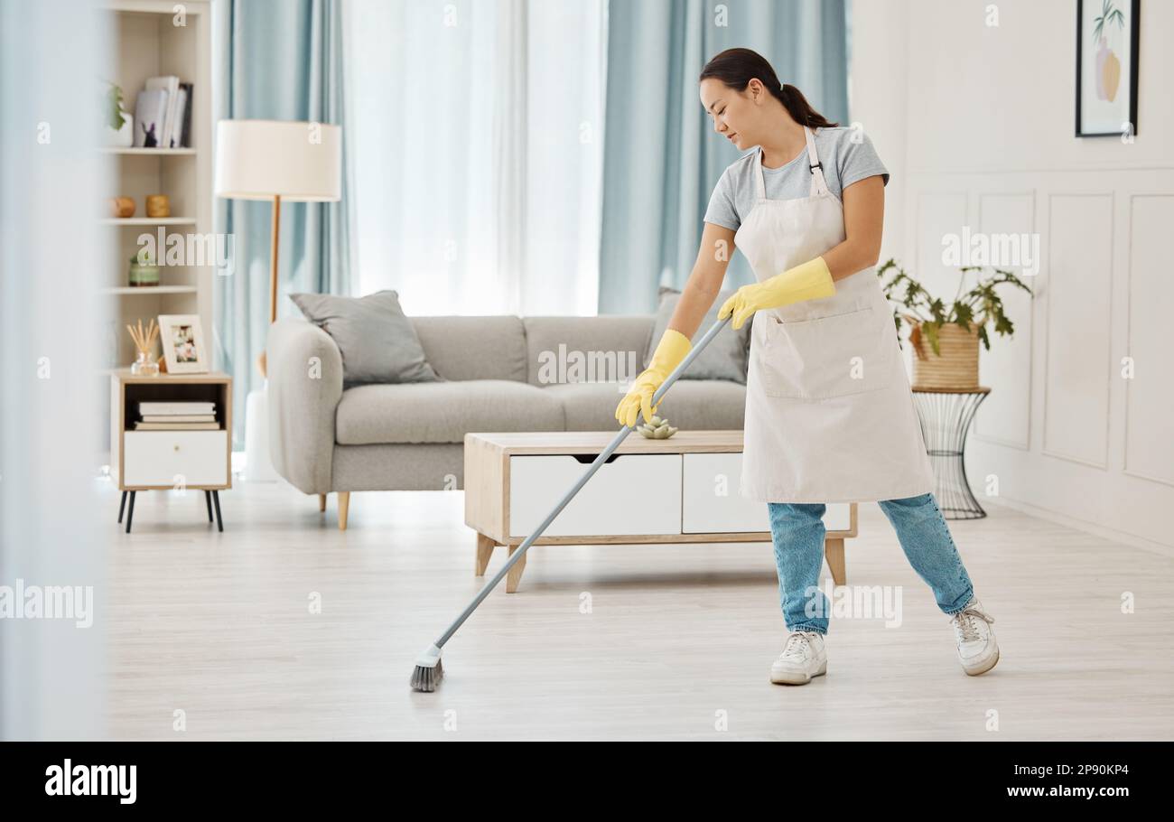 Woman working in a cleaning service mopping the living room floor of a ...
