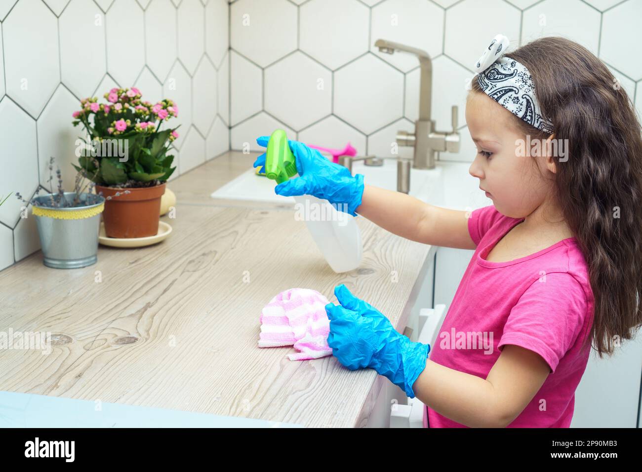 Nice little girl in protective gloves wipe kitchen set with household ...