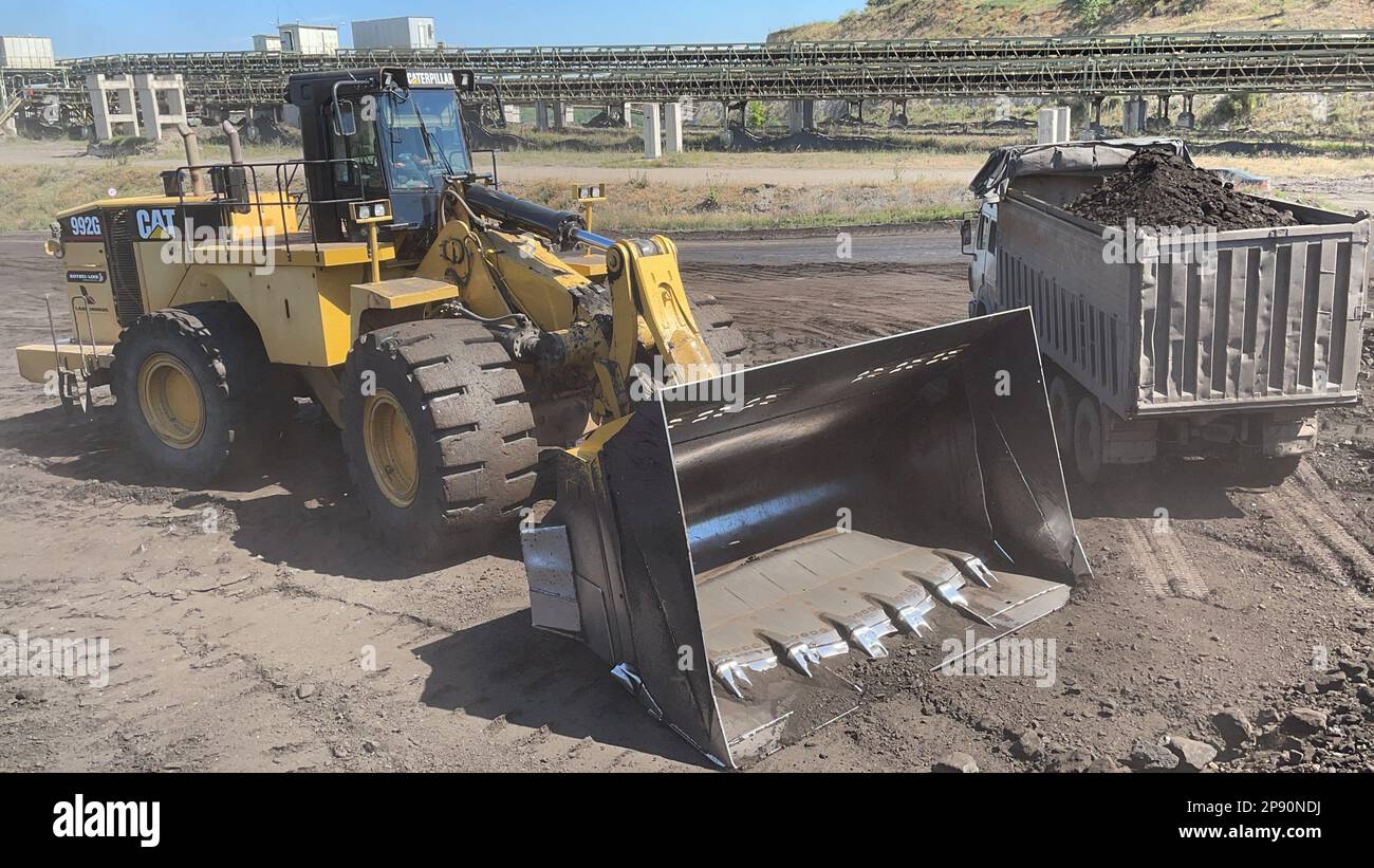 Wheel Loader loading coal on trucks, working at a huge mining site ...