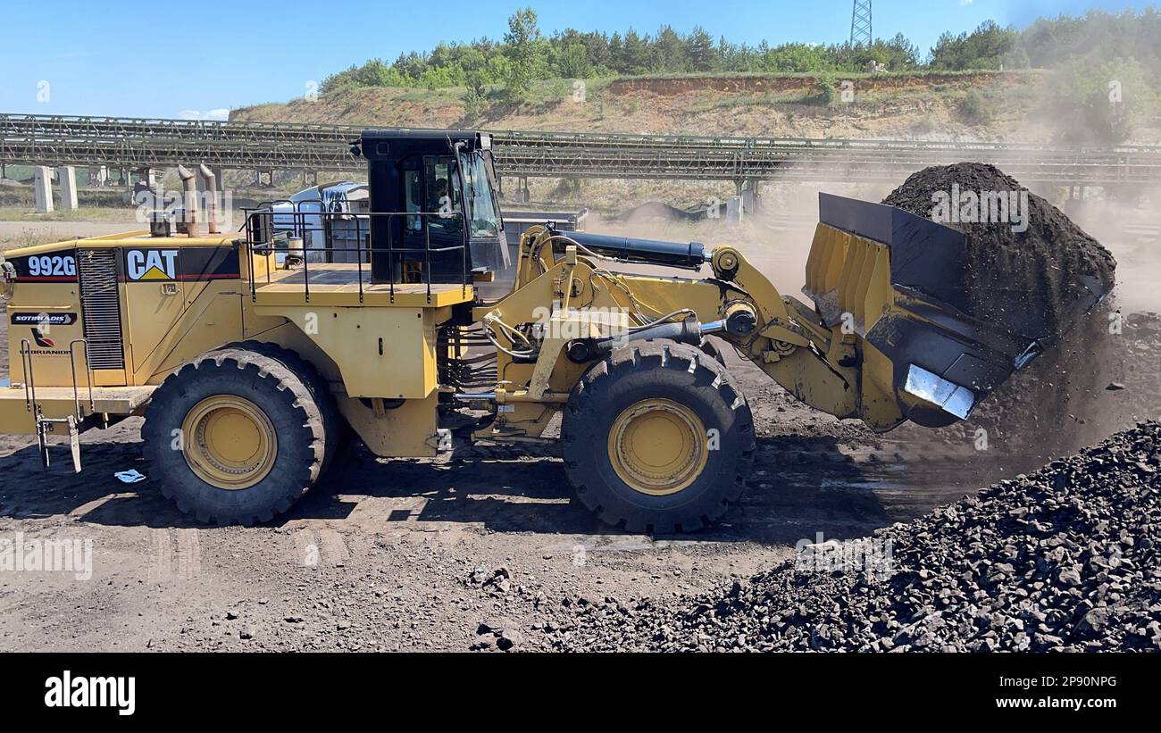 Wheel Loader loading coal on trucks, working at a huge mining site ...
