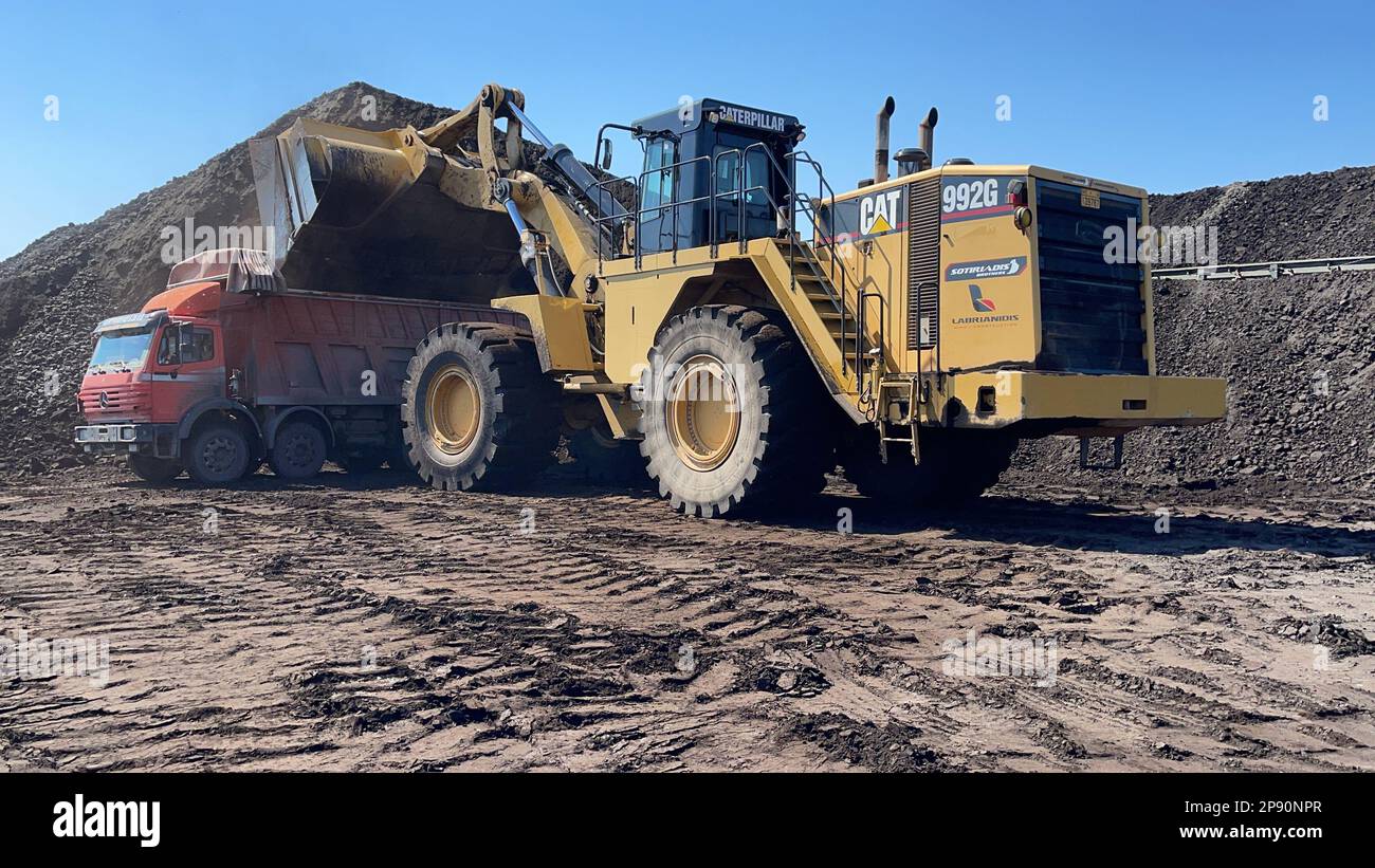 Wheel Loader loading coal on trucks, working at a huge mining site ...