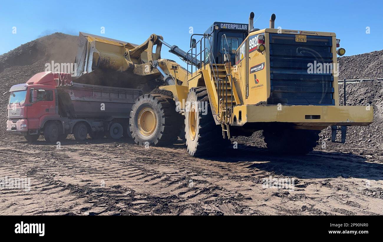 Wheel Loader loading coal on trucks, working at a huge mining site ...