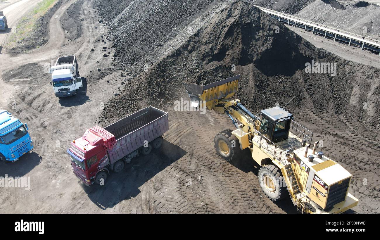 Wheel Loader loading coal on trucks, working at a huge mining site ...