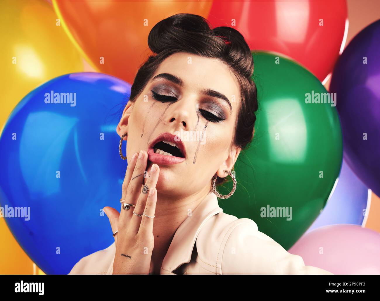 Woman, balloon and sad cry in studio with makeup tears, depression or anxiety at birthday ...