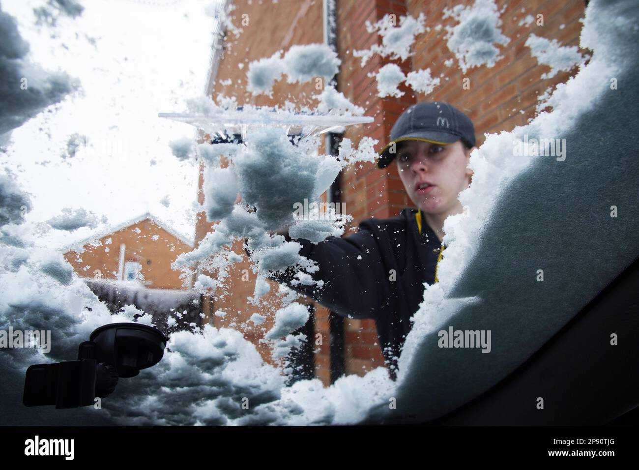 A woman clears snow from a windscreen of a car in Liverpool. Picture date: Friday March 10, 2023 ...
