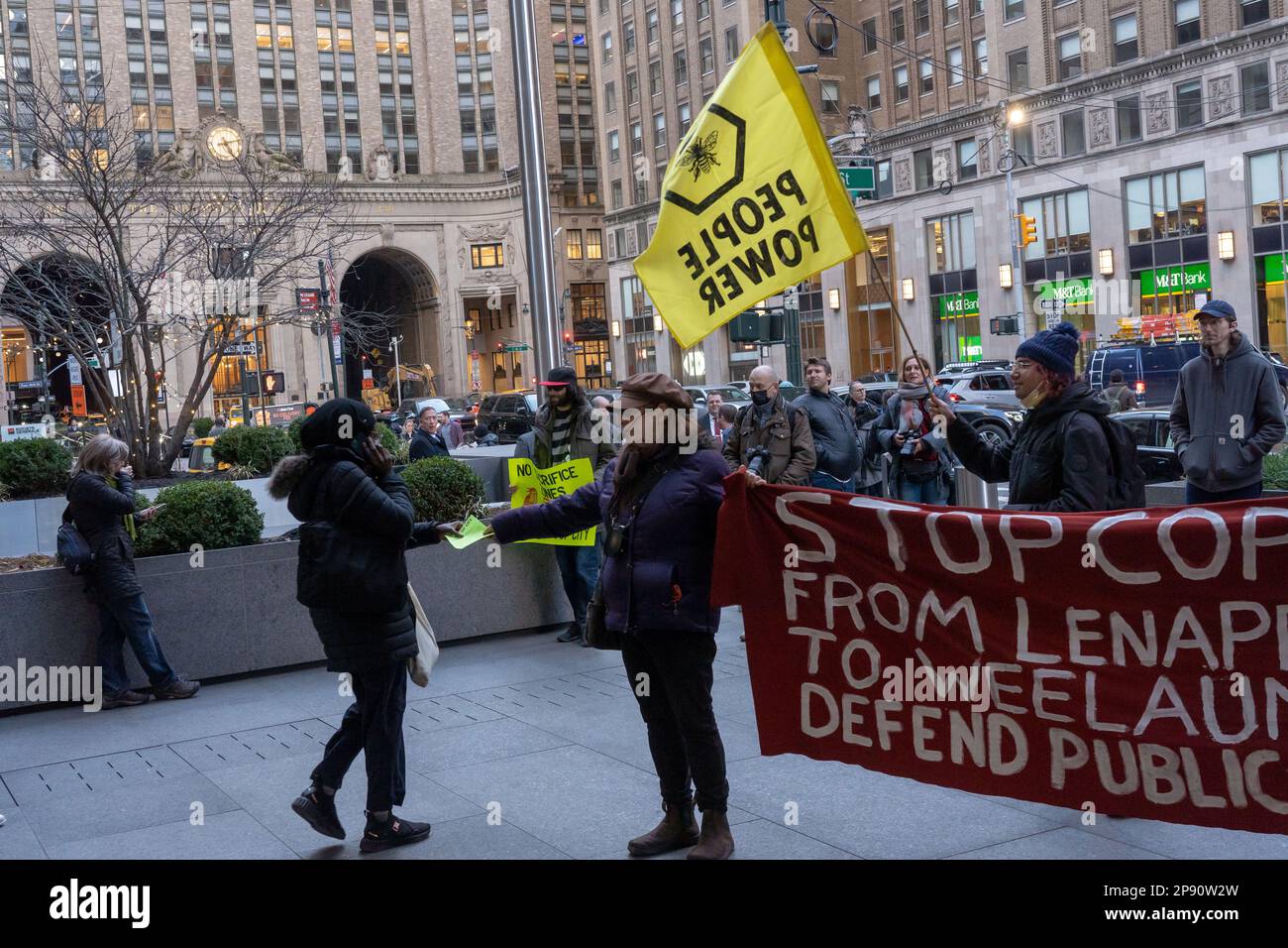 A protester holding a banner hands out leaflets to people exiting the ...