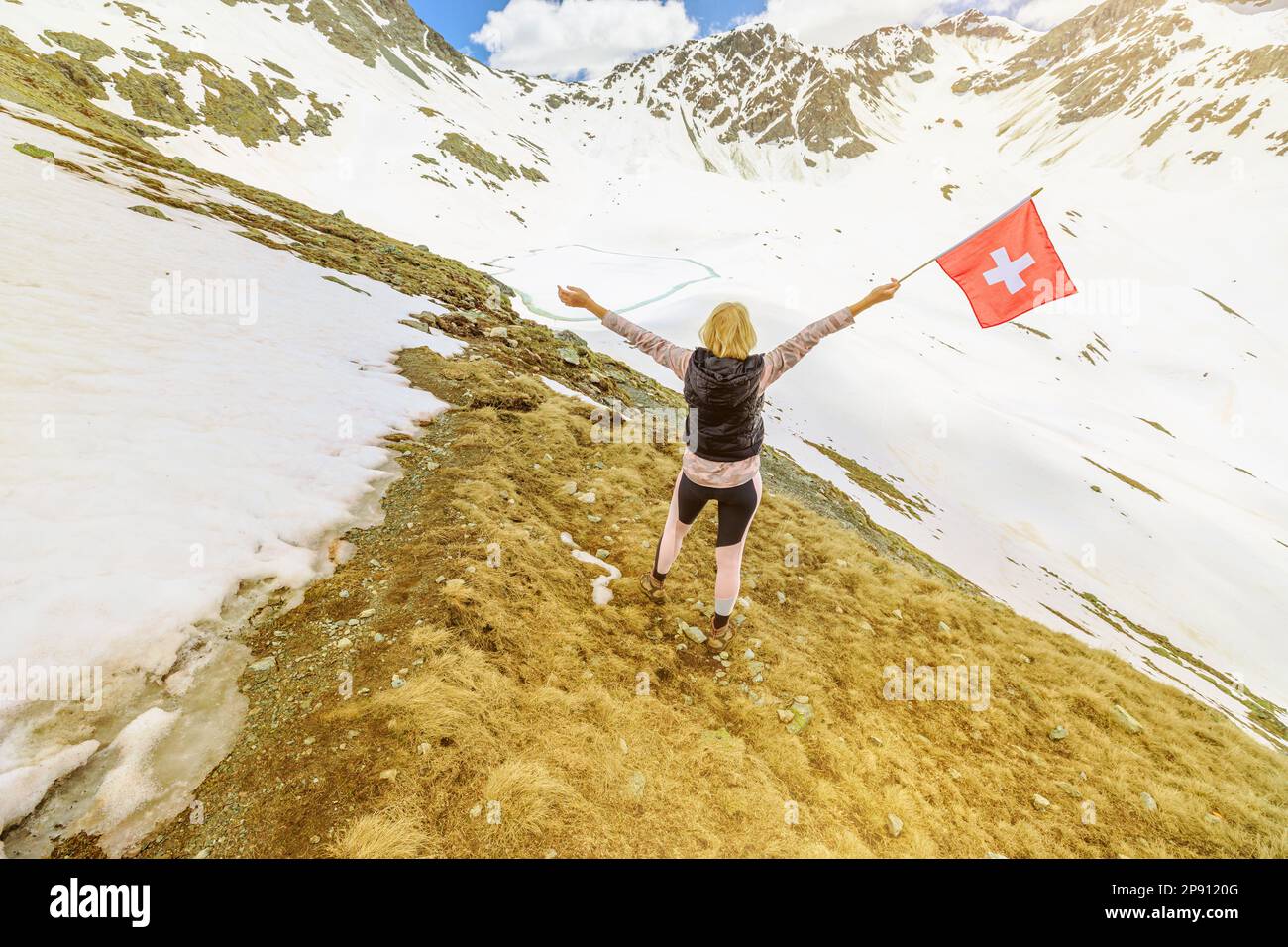 Tourist woman at with swiss flag in the snow on top of Muottas Muragl ...