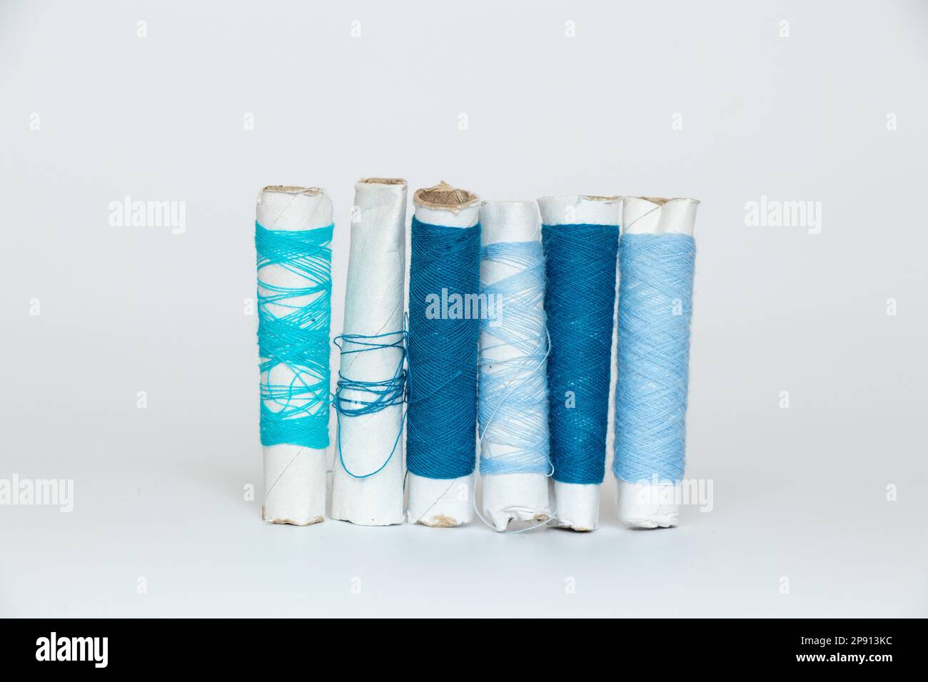 Blue threads of different shades on a spool on a white isolated ...