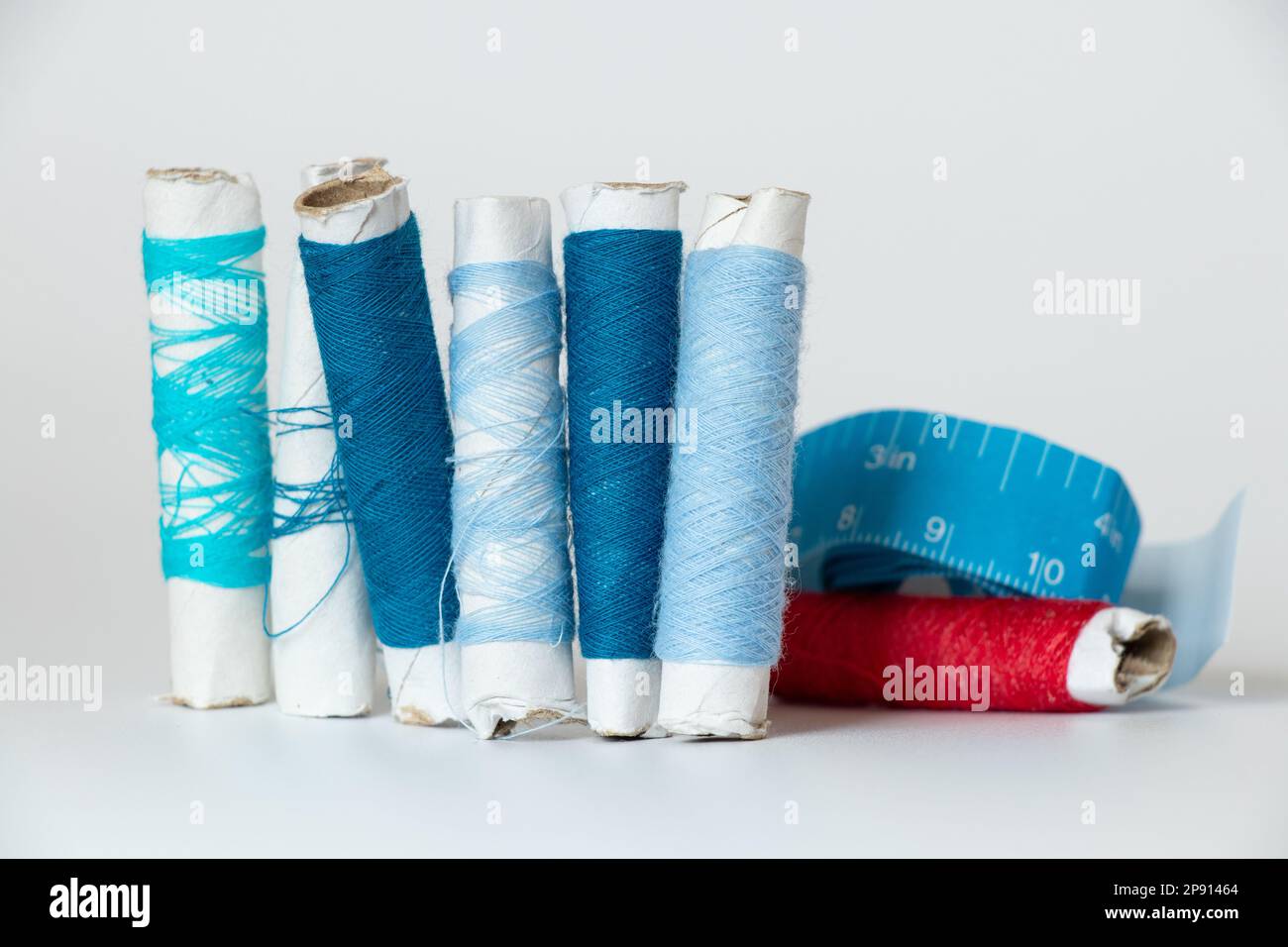 Blue threads and red in different shades on a spool and centimeter tape ...