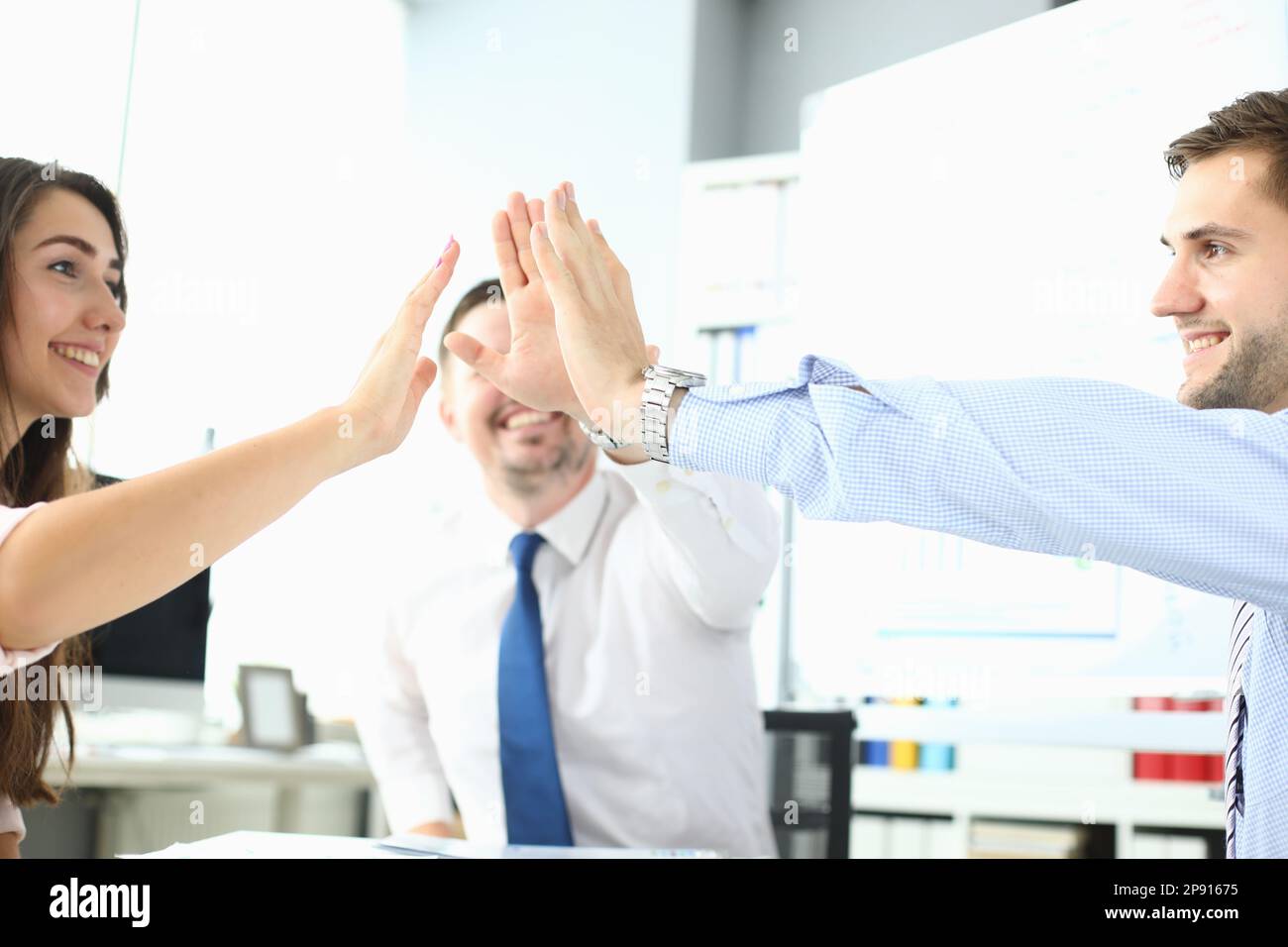 Happy business team high five in office Stock Photo - Alamy