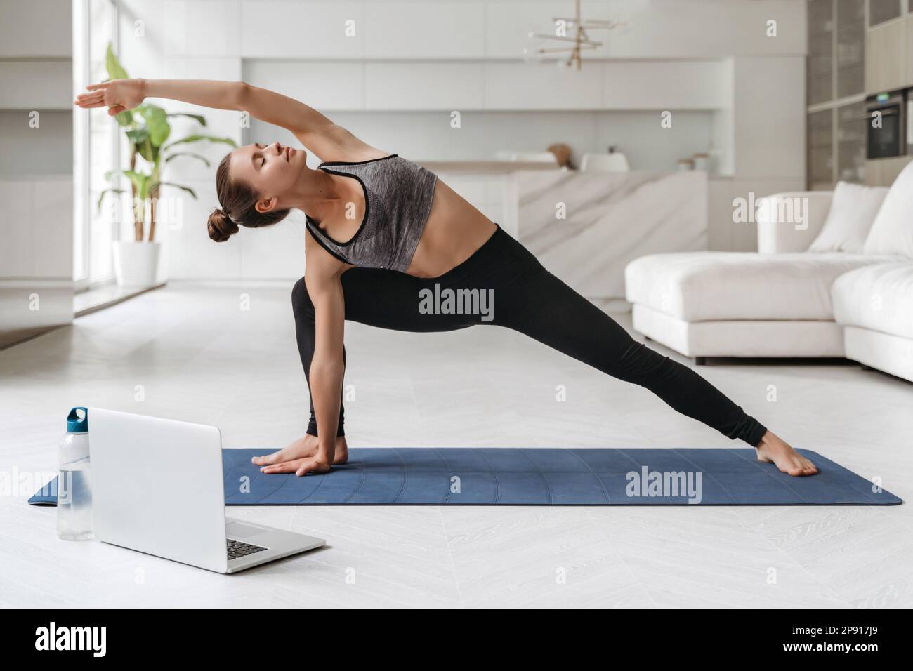 Young attractive woman practicing yoga and stretching body at home ...