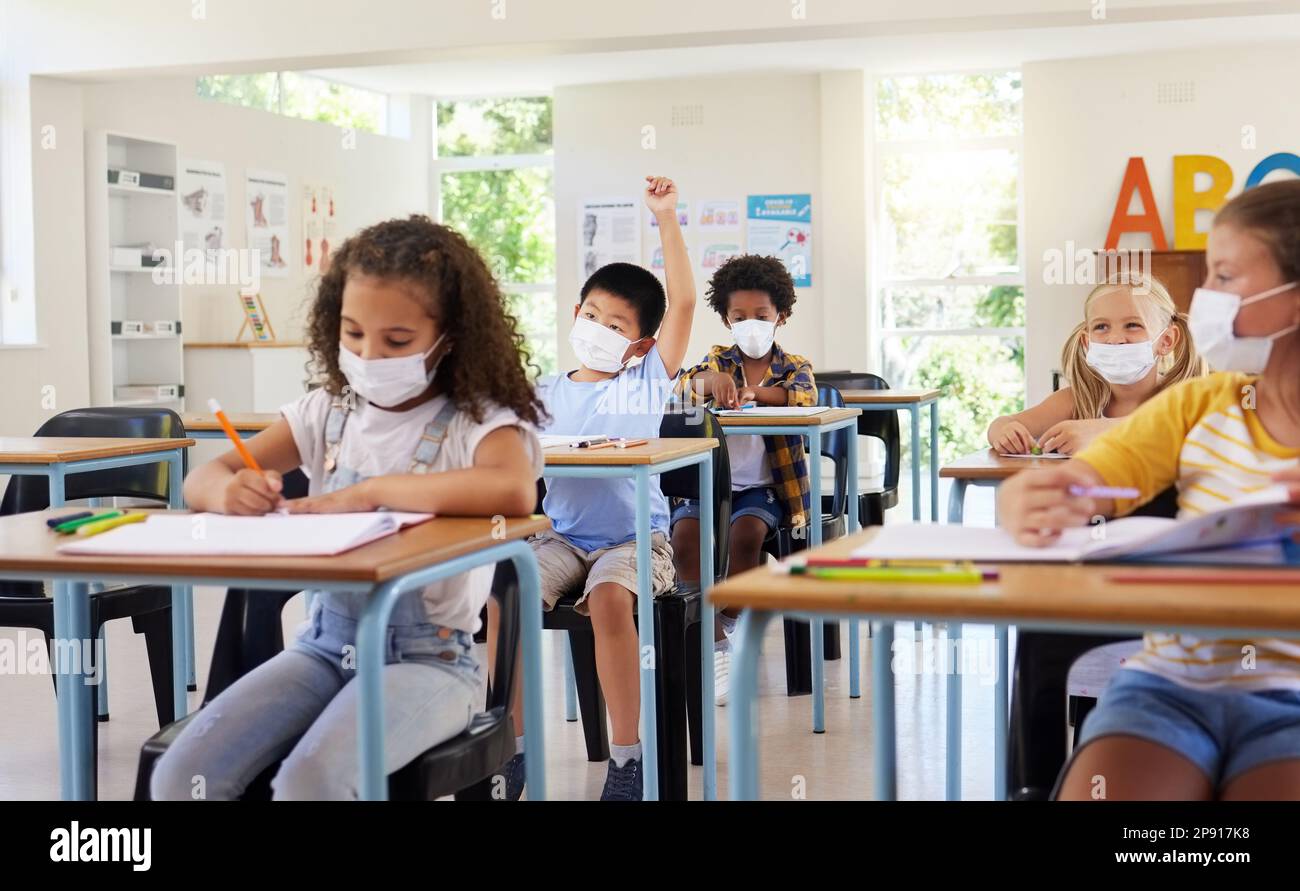 Young kids learning in classroom after covid pandemic, wearing ...