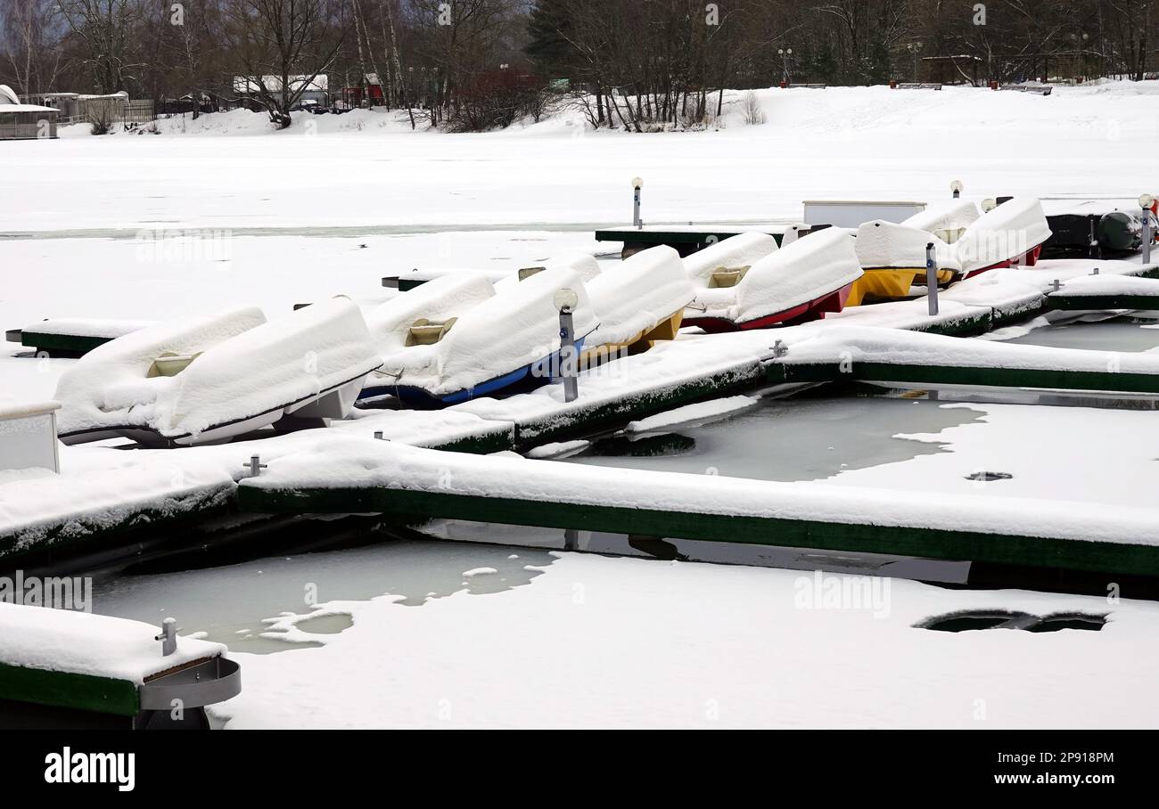 WInter landscape with many overturned boats covered with snow on a dock ...