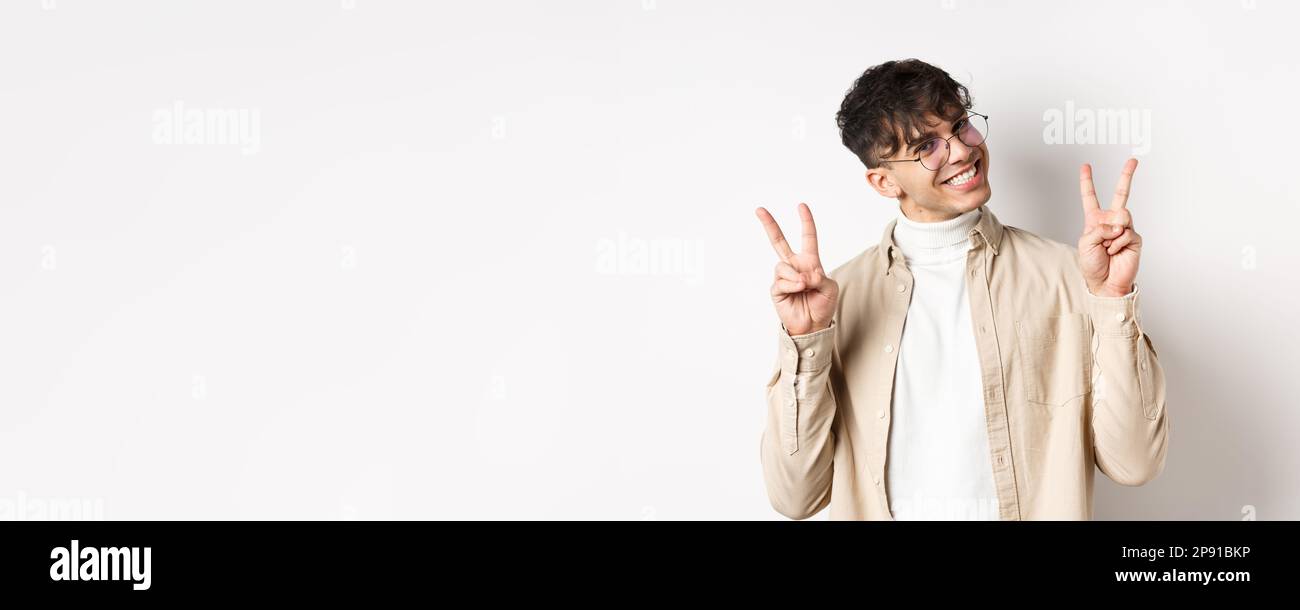 Real people. Handsome hipster guy in glasses showing peace gestures and ...