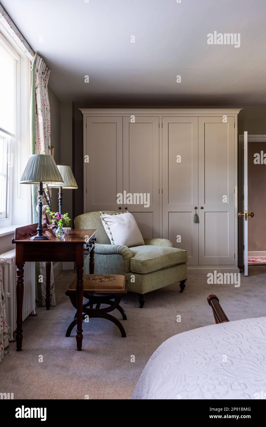 Green armchair, wardrobe and dressing table at window in renovated 18th ...