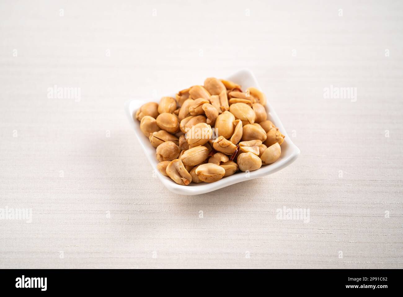 Spicy flavored peanut kernel in a bowl on white table background Stock ...