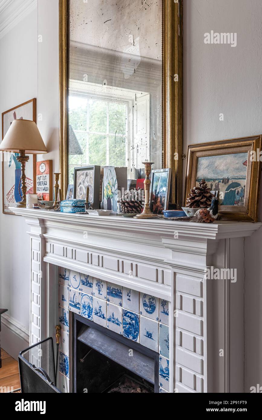 Gilt framed mirror and artwork on delft tiled fireplace in Wiveton Hall ...