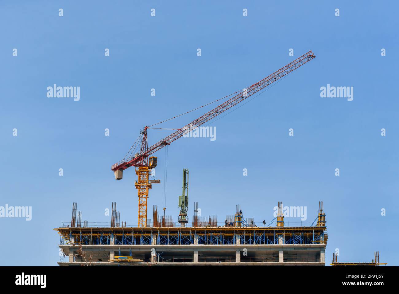 A crane building a modern skyscraper against a blue sky. Construction ...
