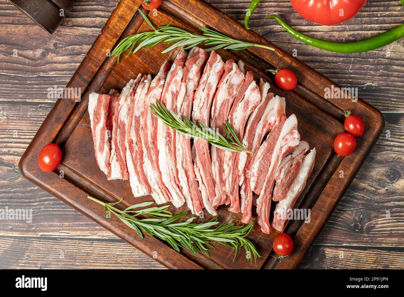 Fresh raw lamb spare ribs. Uncooked sliced lamb ribs on a wood serving ...