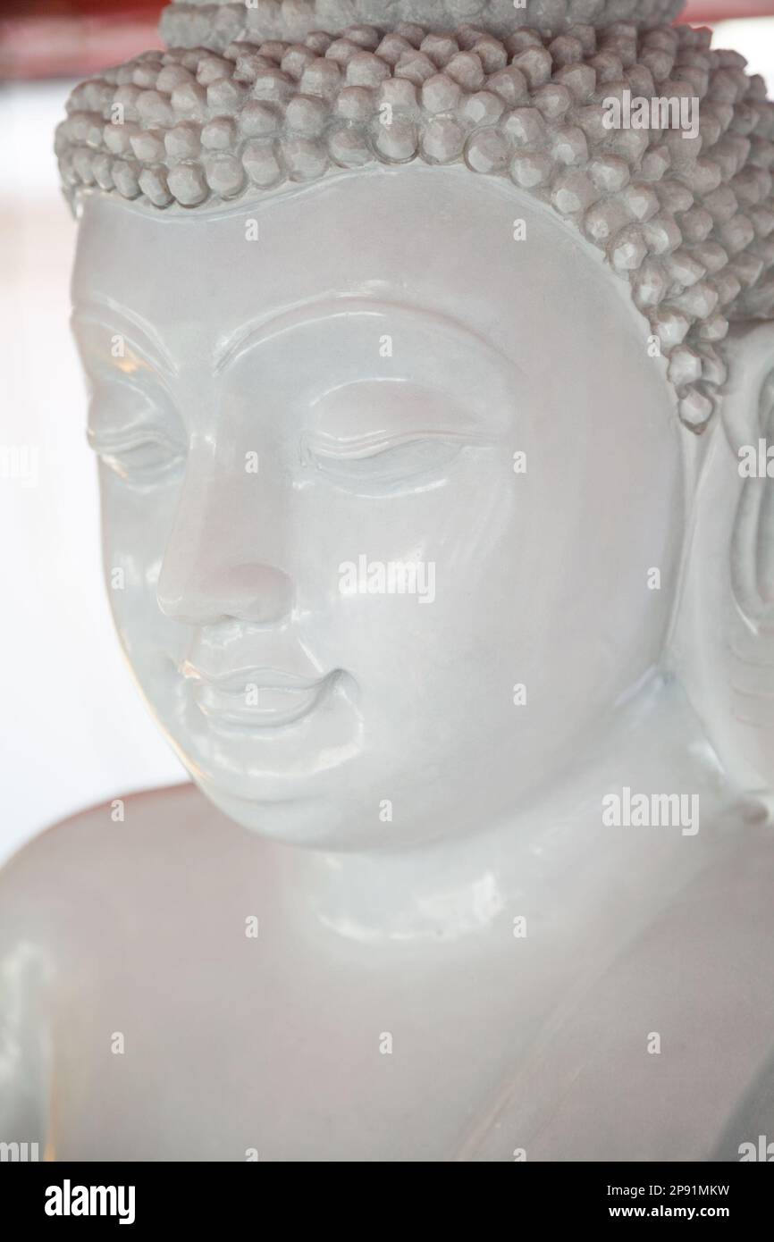 White peaceful Buddha statue meditating with closed eyes close-up ...