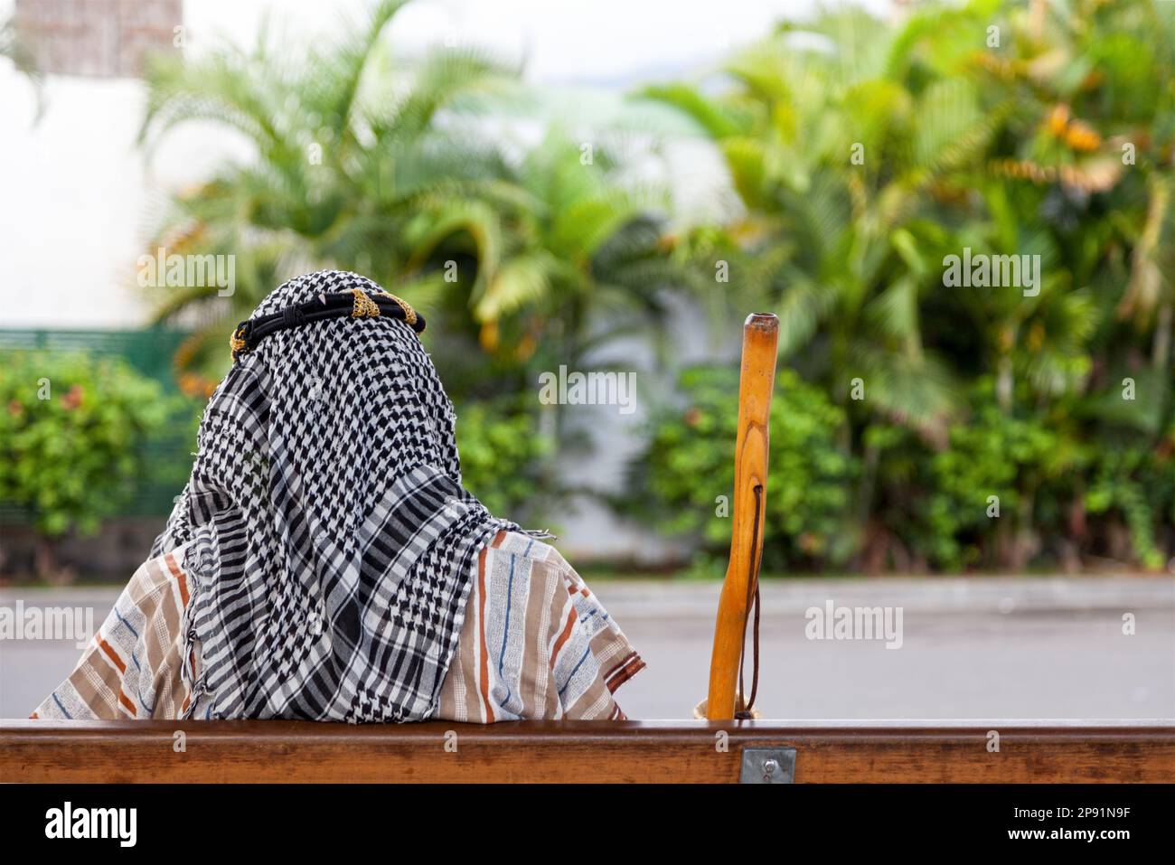 Muslim in traditional clothing sitting on a bench beside his pilgrim ...