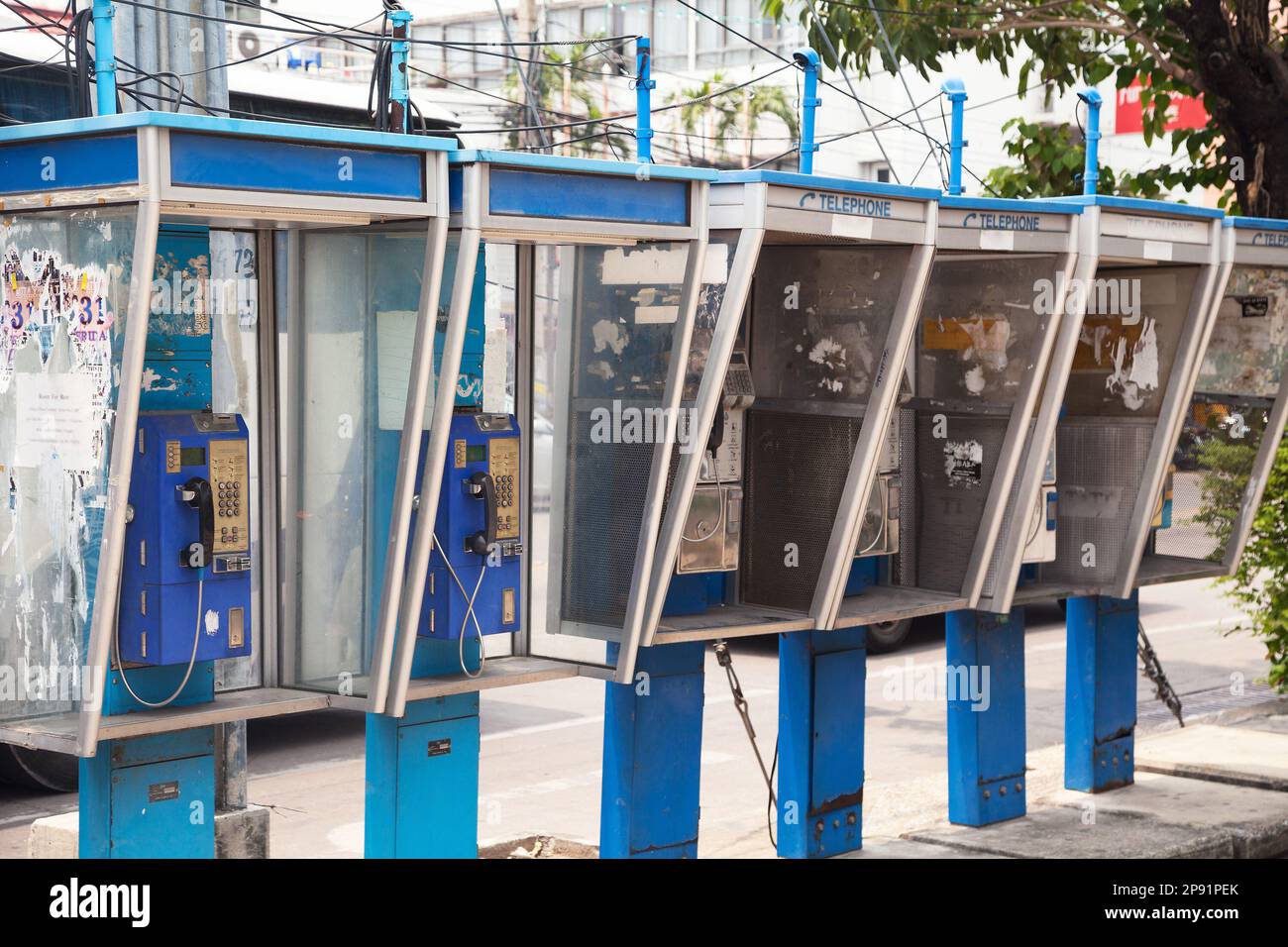 Row of old dirty payphones on a street in Thailand. Group of blue messy ...