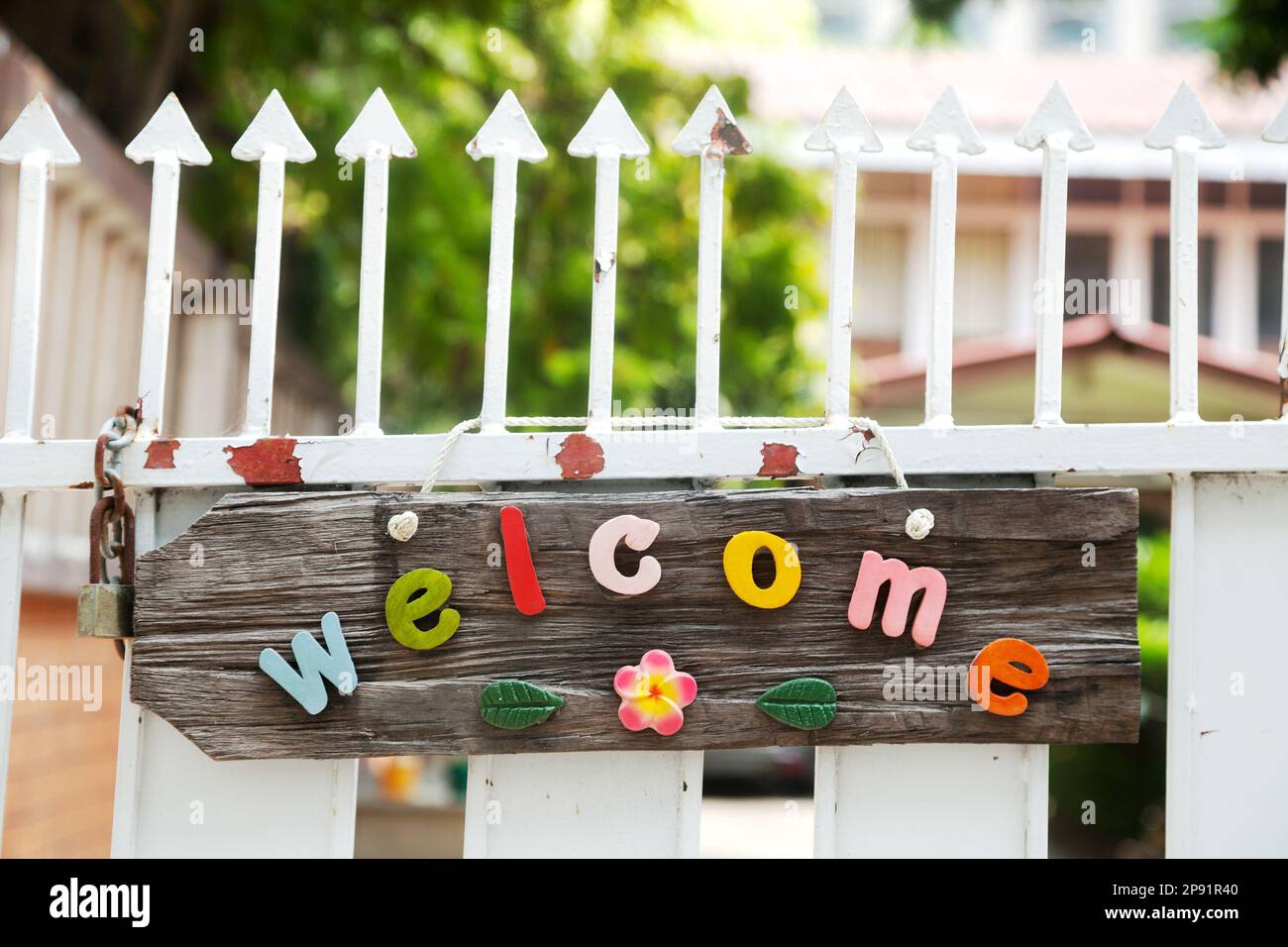 Fun colorful wooden welcome sign hanging on a white spiked fence Stock ...