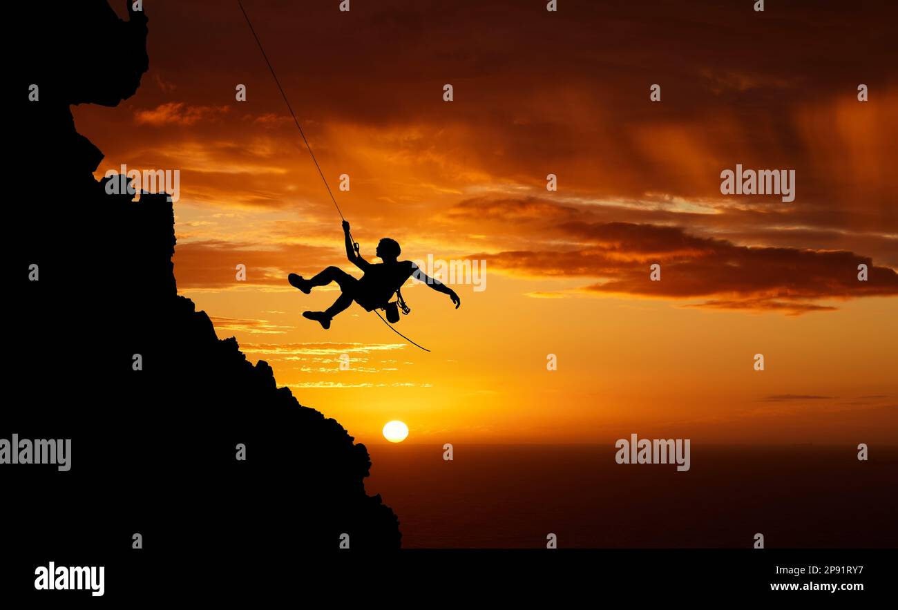 Sunset sky abseiling, mountain silhouette and hiking man hanging on ...