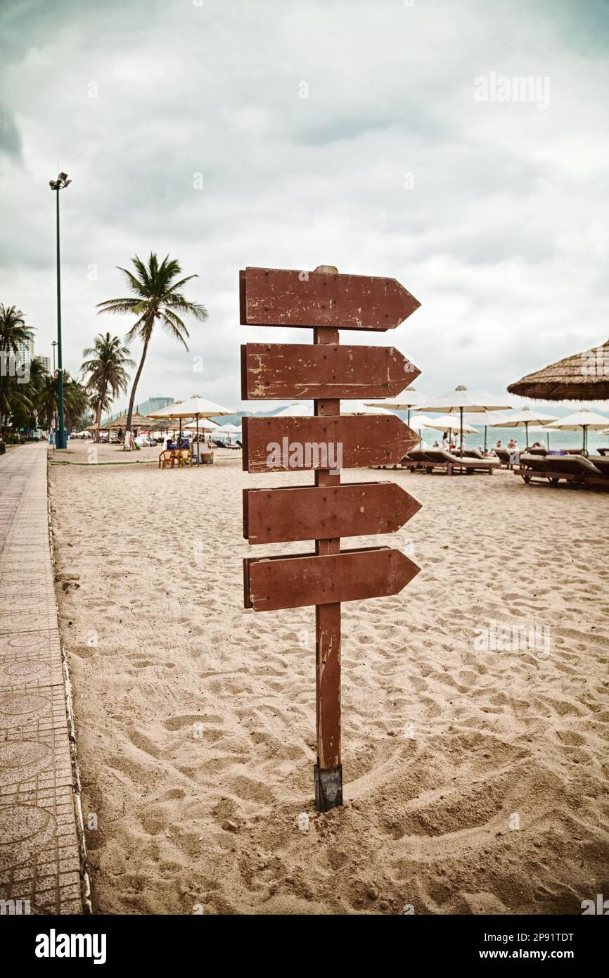 Wooden pointer post with copy space at the beach. Blank arrows on a ...