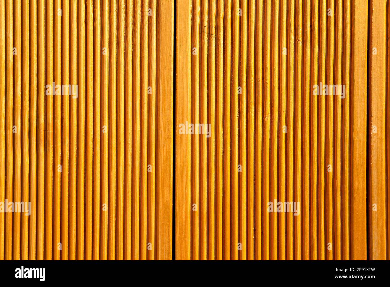Yellow wooden wall panels decorated with vertical grooves. Abstract ...