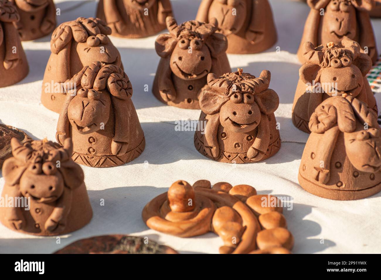 Clay figurines of animals, clay handmade sheep and cow in the rays of ...