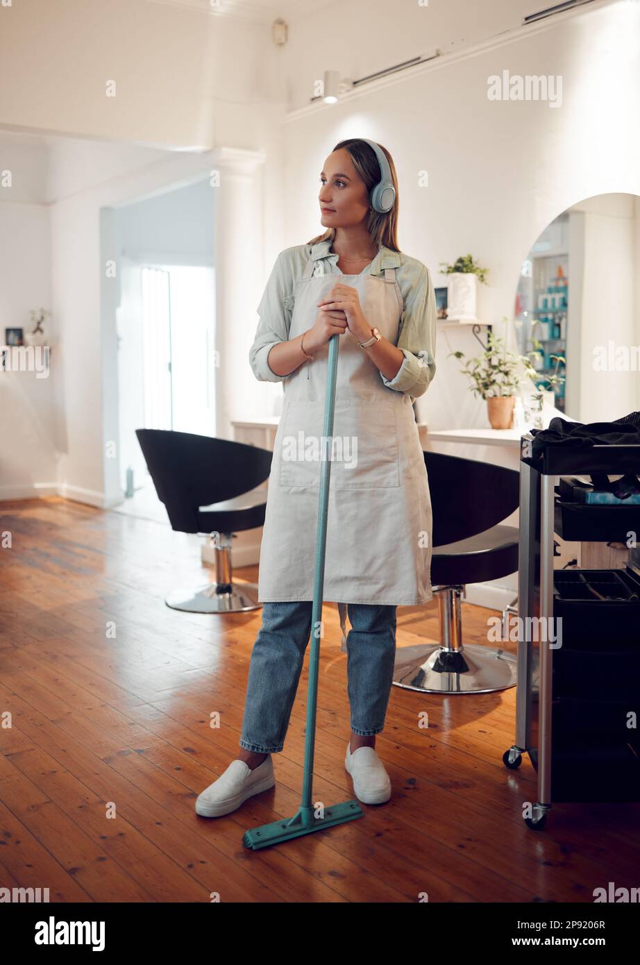 Salon, headphones and woman cleaner sweeping her workplace while ...