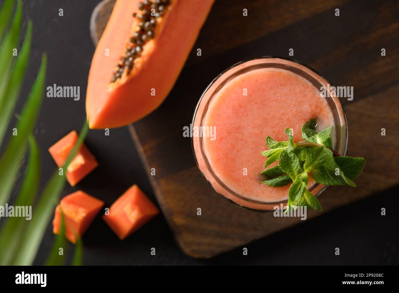 Asian traditional Papaya lassi served with mint on dark background ...
