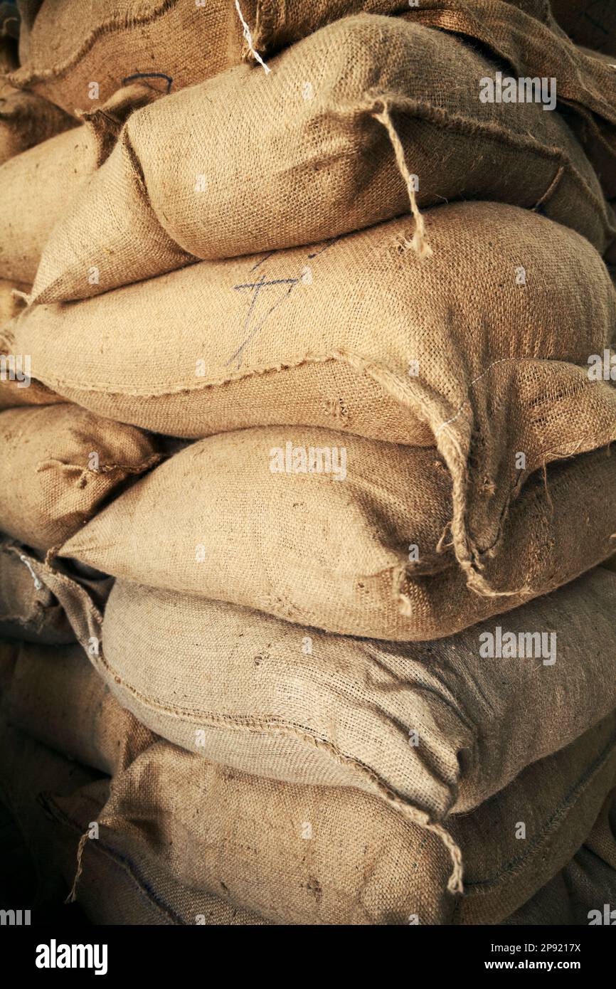 Stack of brown burlap sacks with grain at a warehouse. Big pile of hemp ...