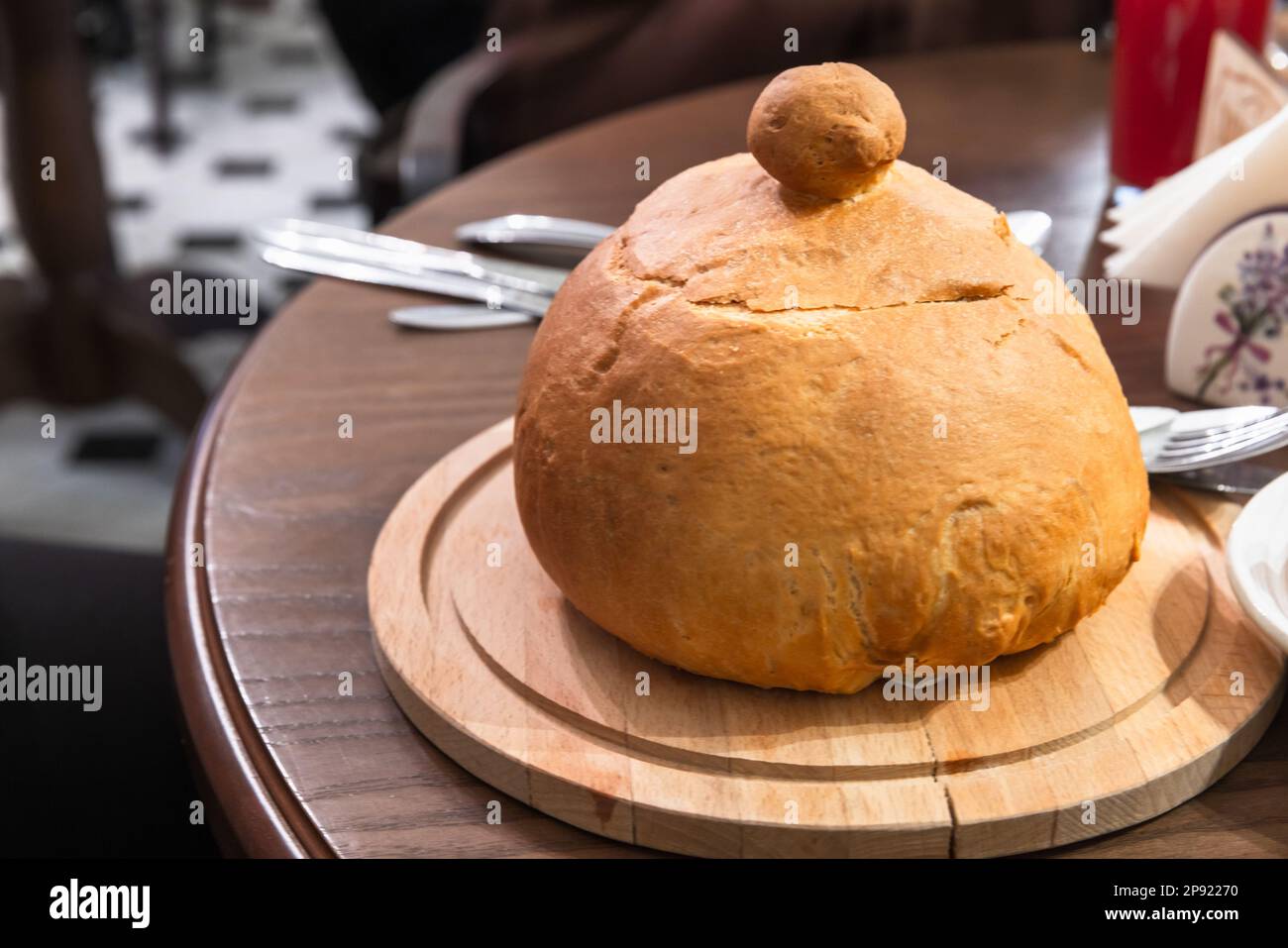 Homemade bread bowl soup stands on the wooden table, close up photo ...