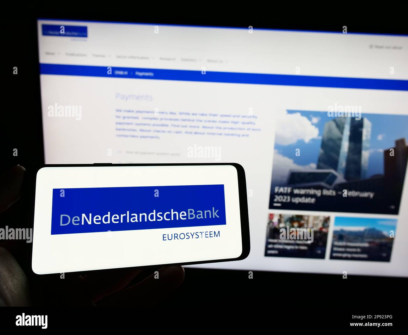 Person holding mobile phone with logo of Dutch central bank De ...