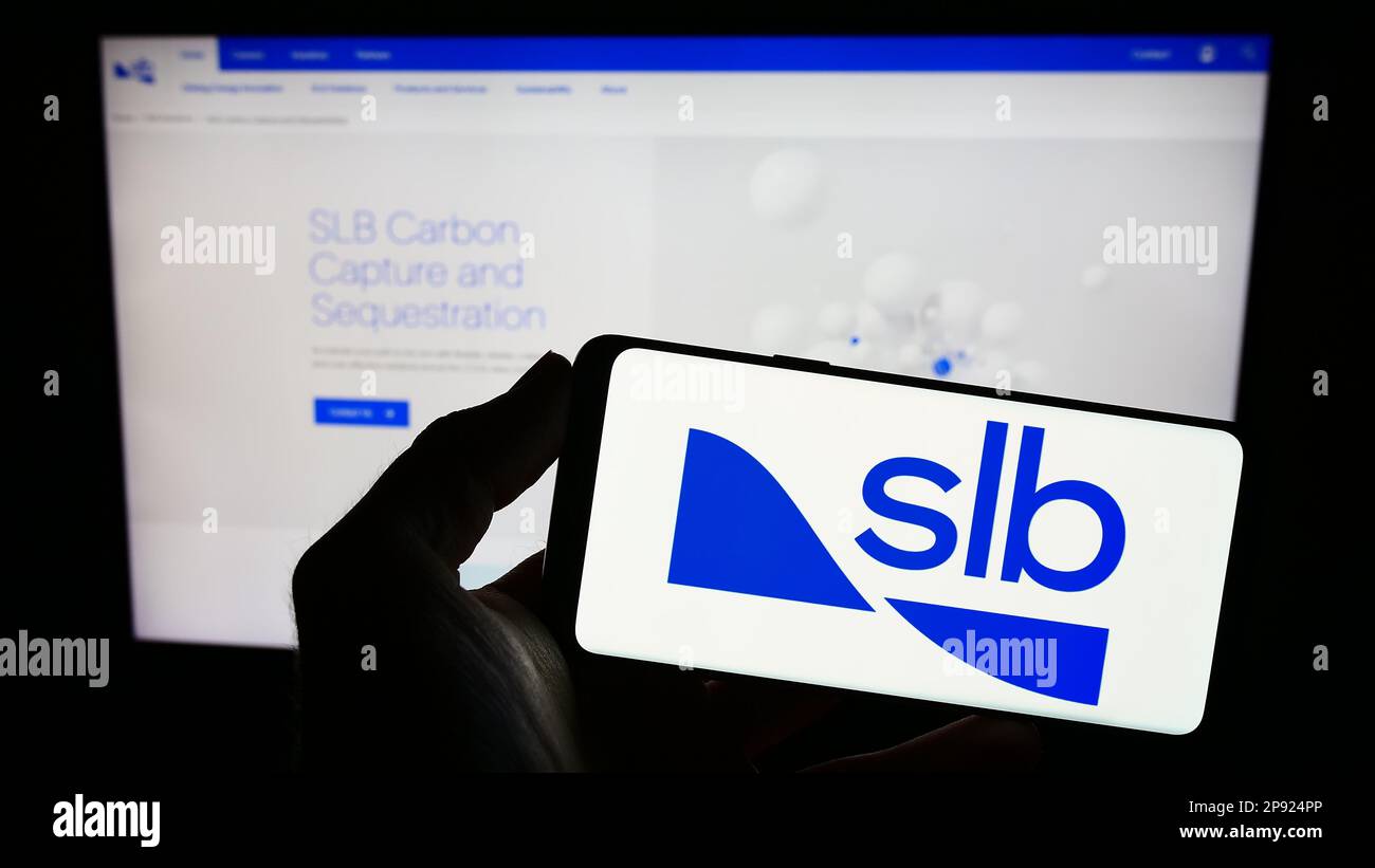 Person holding smartphone with logo of oilfield company Schlumberger ...