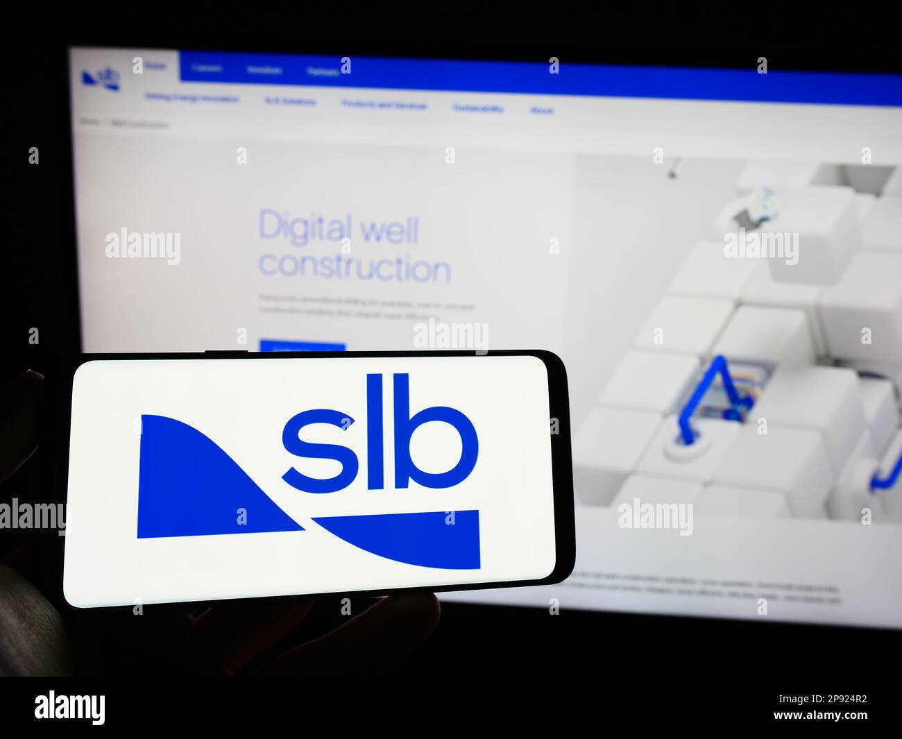 Person holding mobile phone with logo of oilfield company Schlumberger ...