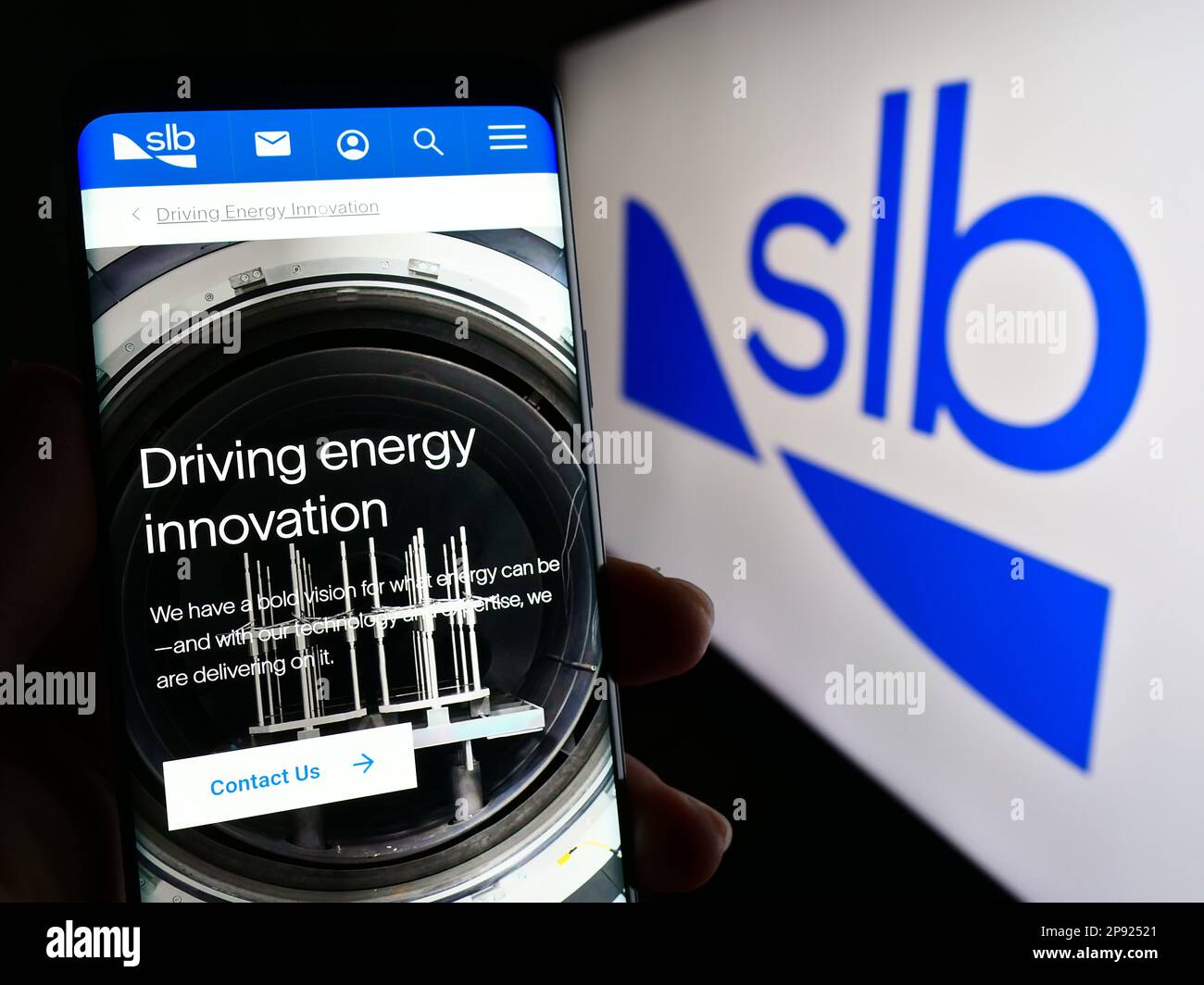 Person holding cellphone with webpage of oilfield company Schlumberger ... Person holding cellphone with webpage of oilfield company Schlumberger ...