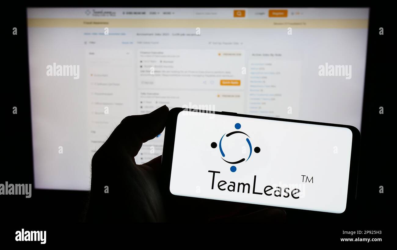 Person holding mobile phone with logo of Indian job company TeamLease ...