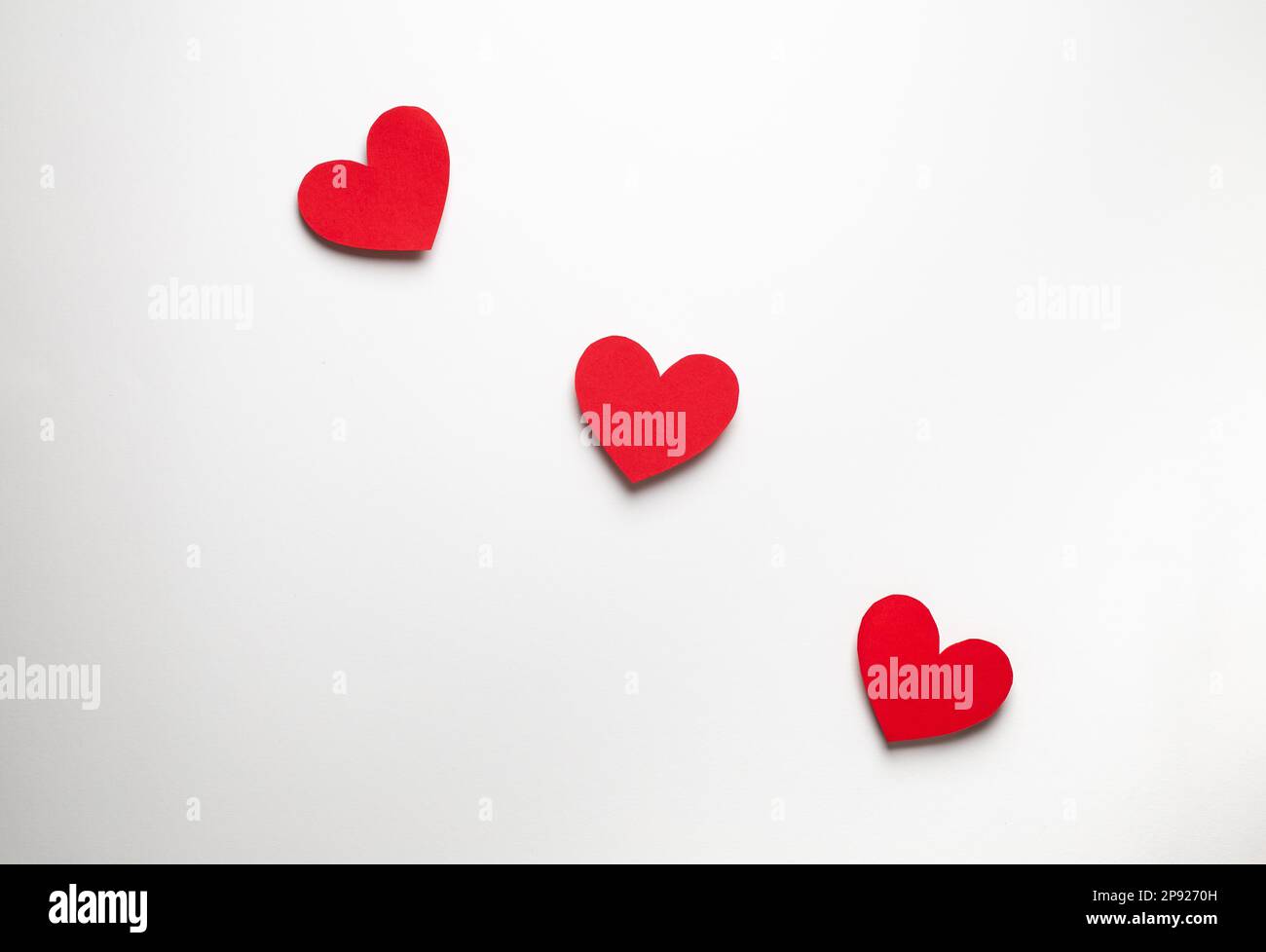Three red hearts in a row cut from paper on white background, craft ...