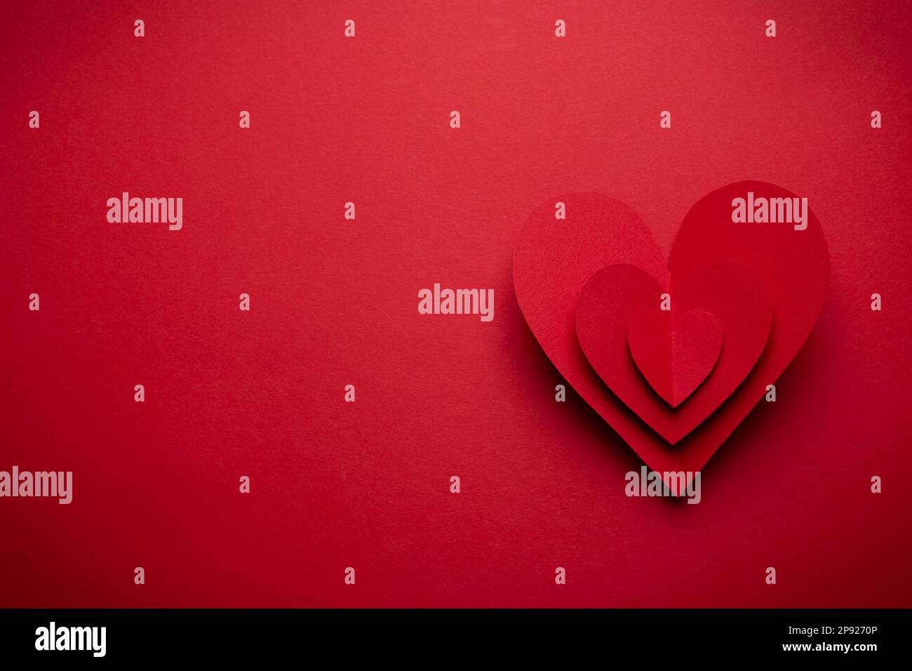 Big voluminous red heart cut from paper on red monochrome background ...