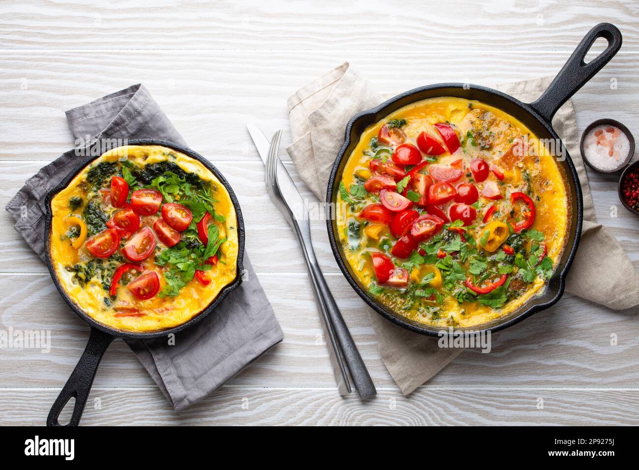 Healthy frittata in two cast iron pans with fried beaten eggs and ...