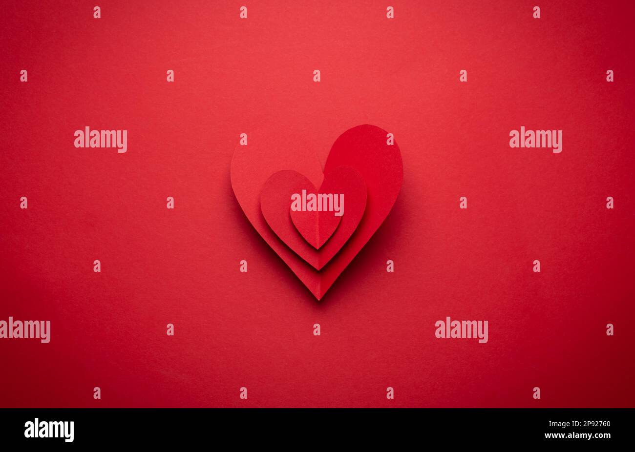 Big voluminous red heart cut from paper on red monochrome background ...