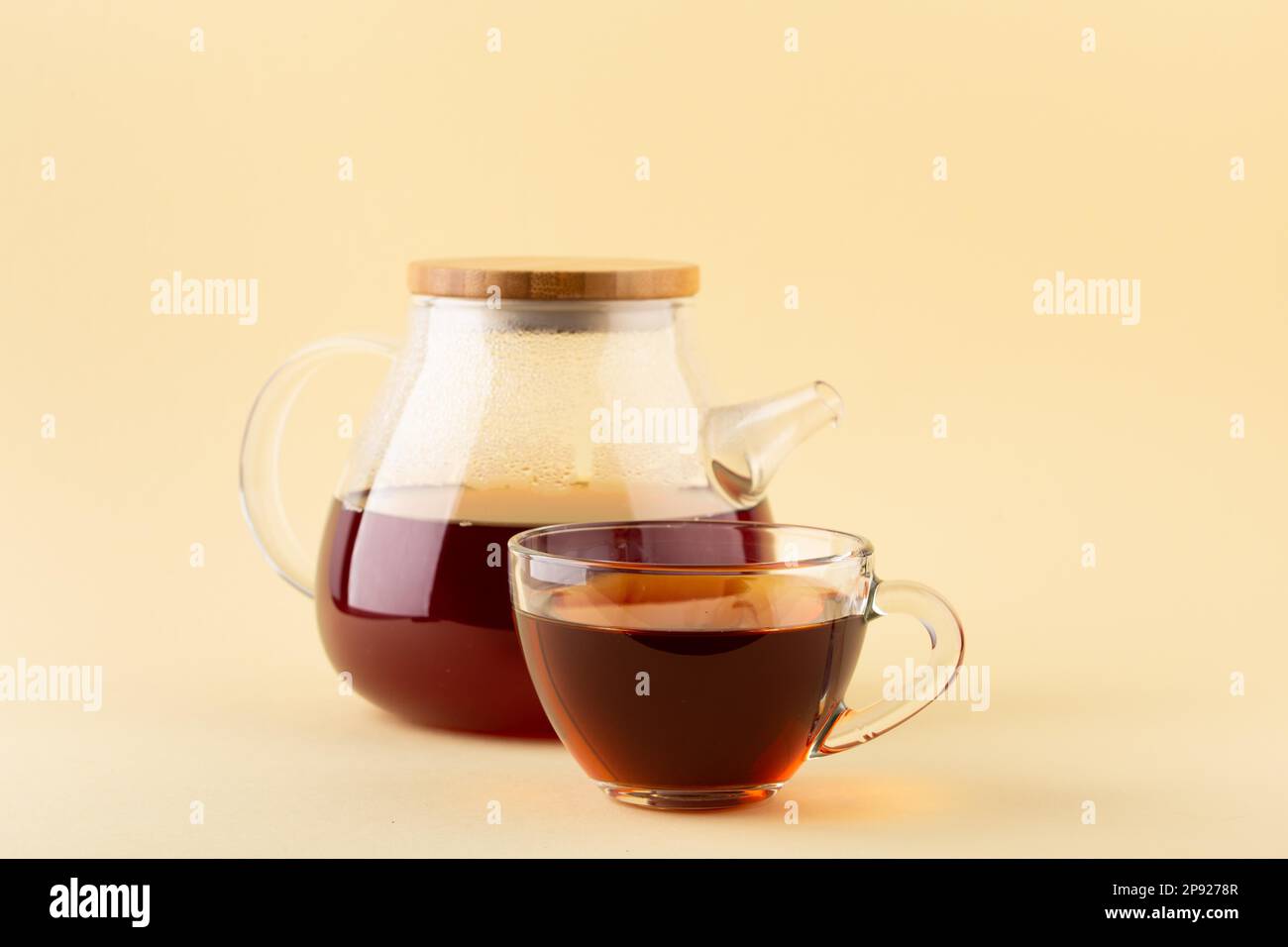 Freshly brewed organic black tea in transparent glass teapot and in ...