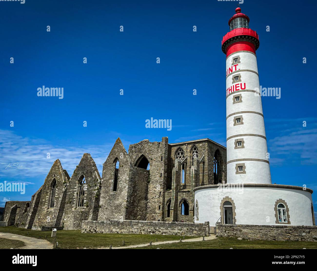 A lighthouse in front of the ruins of a castle in Plougonvelin, France ...