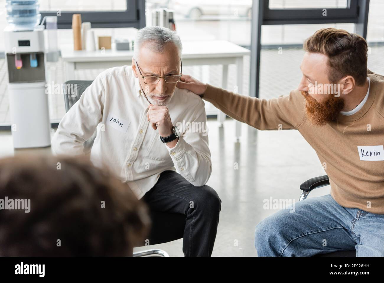 Man calming mature person with alcohol addiction during group therapy ...