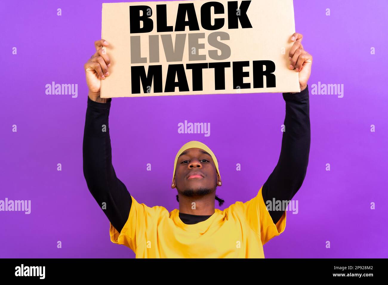 Black ethnic man in yellow clothes on a purple background, pointing ...
