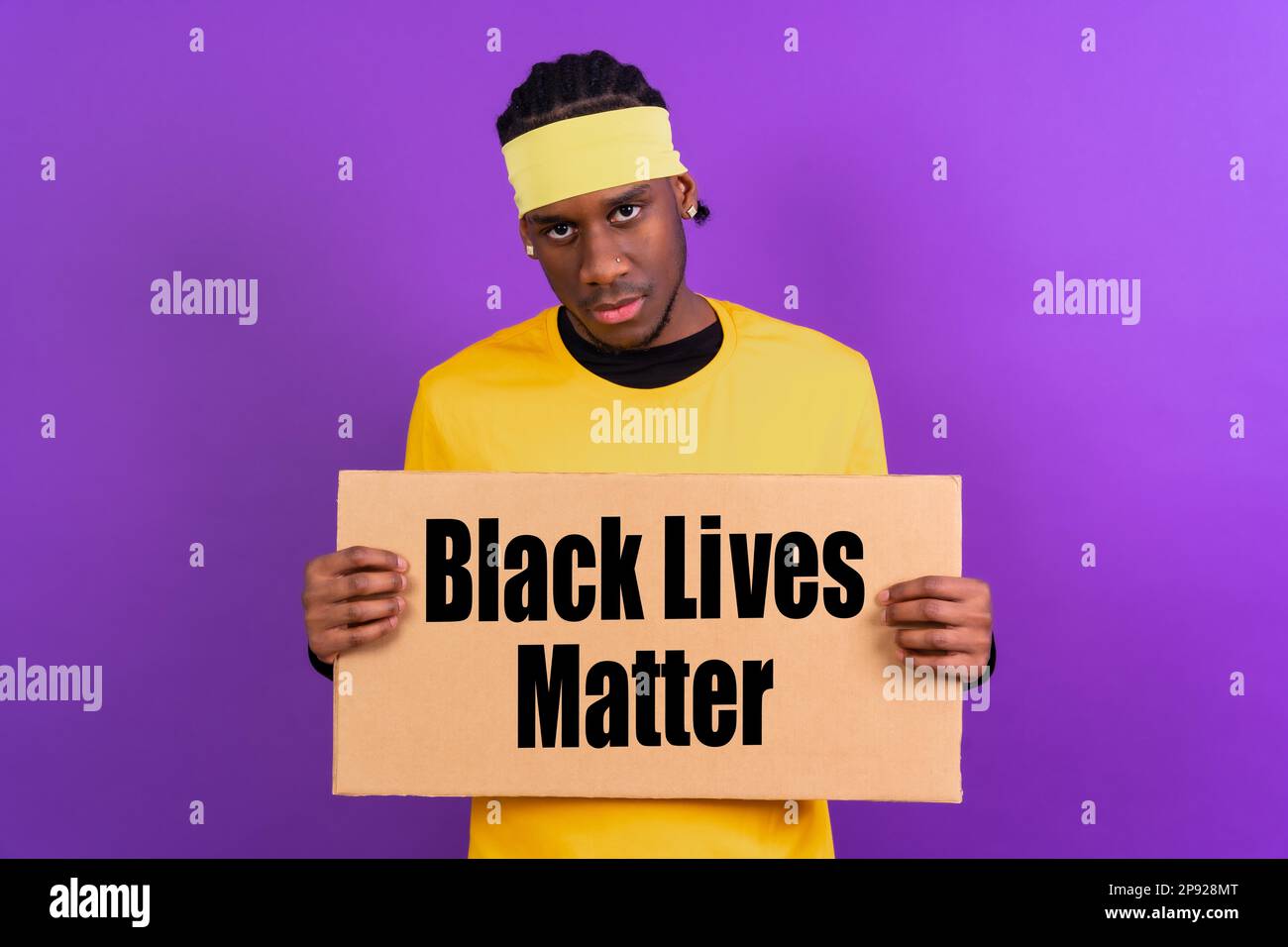 Black ethnic man in yellow clothes on a purple background, pointing ...