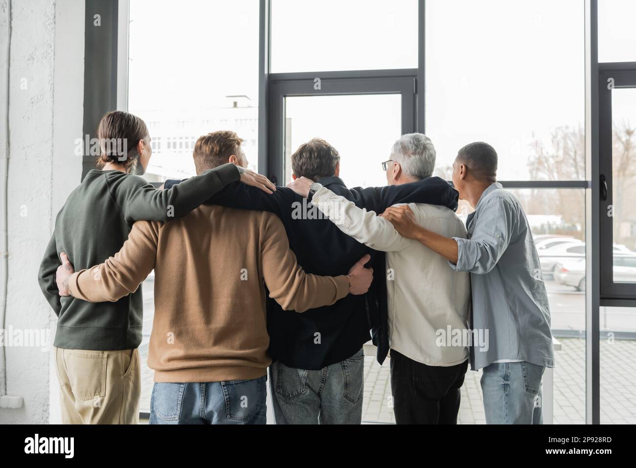 Back view of interracial group of anonymous alcoholics hugging during ...